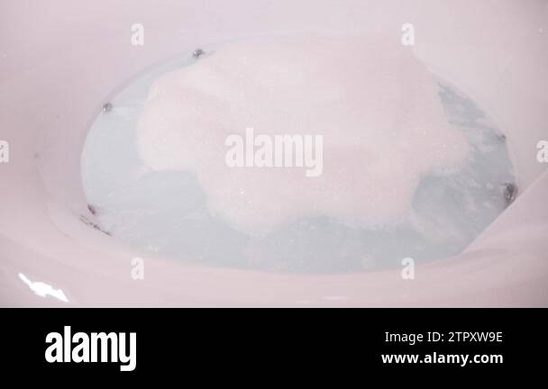 A modern round bath with a jacuzzi, filled with bubbling water with soap foam, without people in ...