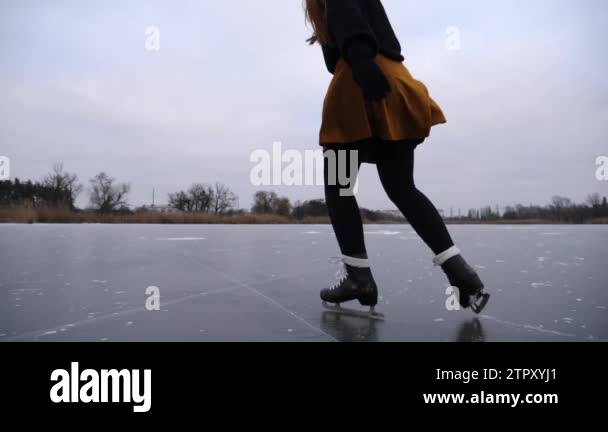 Young sportswoman falling on ice rink while training elements outdoor ...