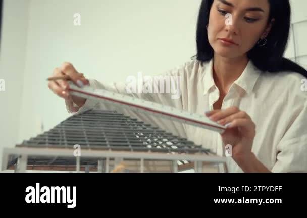 Professional young beautiful architect engineer using ruler and pencil measuring model roof ...