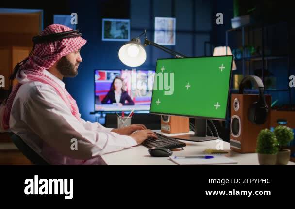 Arabic man looking at chroma key computer screen while working from ...