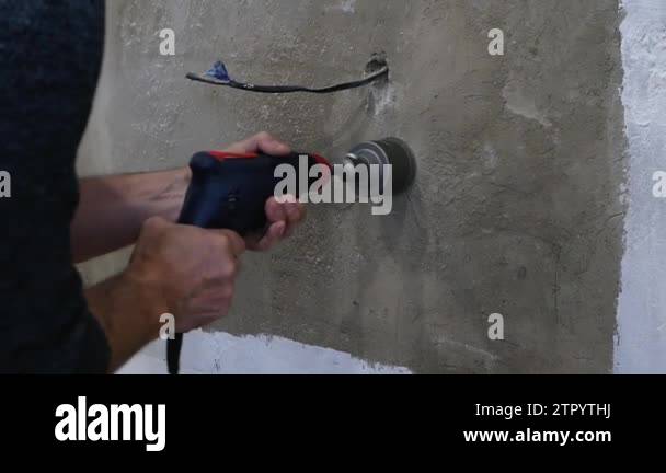 Installation of socket boxes in the wall. A male worker is drilling a ...