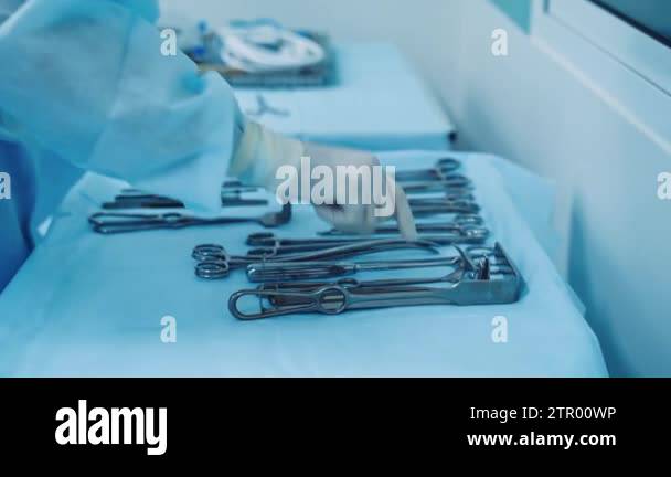 Sterile medical tools on the table. Nurse in latex gloves laying out ...