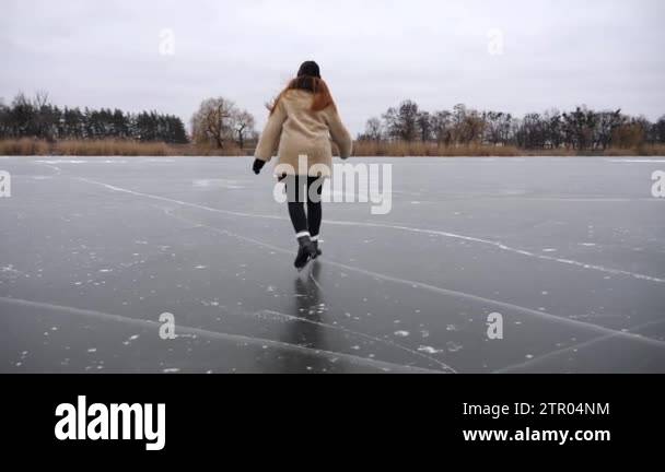 Lady in fur coat skating on frozen river at cloudy day. Woman shod in ...