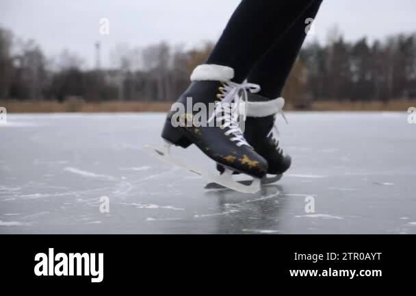 Legs of woman shod in figure skates sliding on ice surface at nature ...