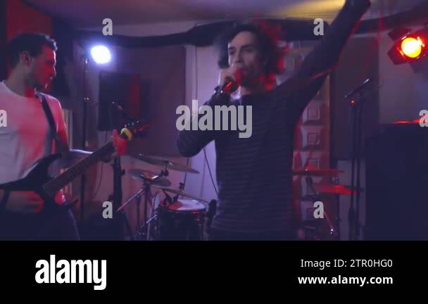 The vocalist of the rock band loudly shouts words into the microphone ...