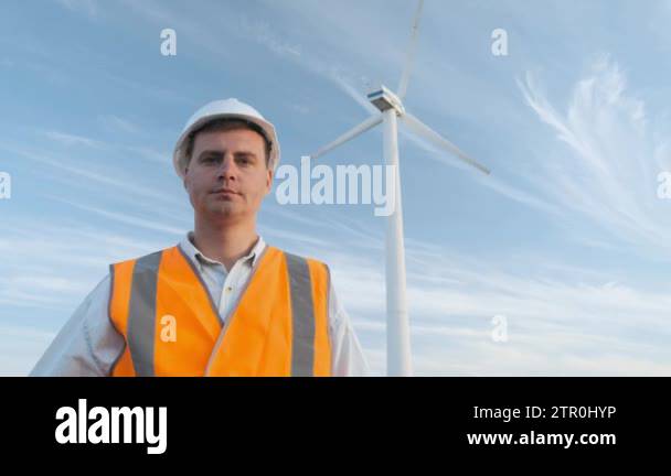 portrait: the male engineer projects the work near the wind turbine ...