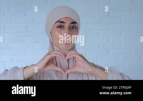 Beautiful Muslim woman shows heart with hands and smiles at camera ...