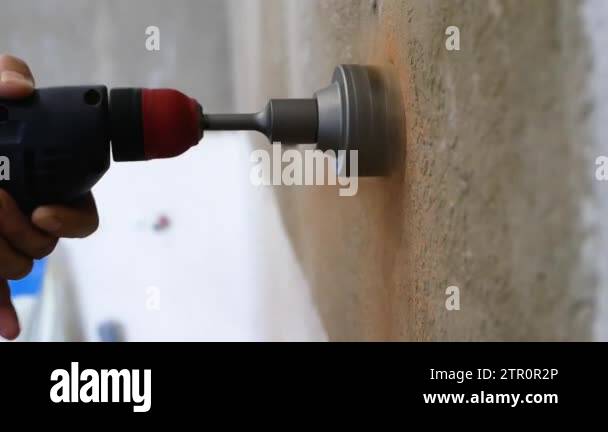 Installation of socket boxes in a brick wall. A male worker is drilling ...