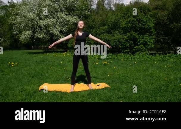 A beautiful young girl with a long braid makes a warm-up in nature ...