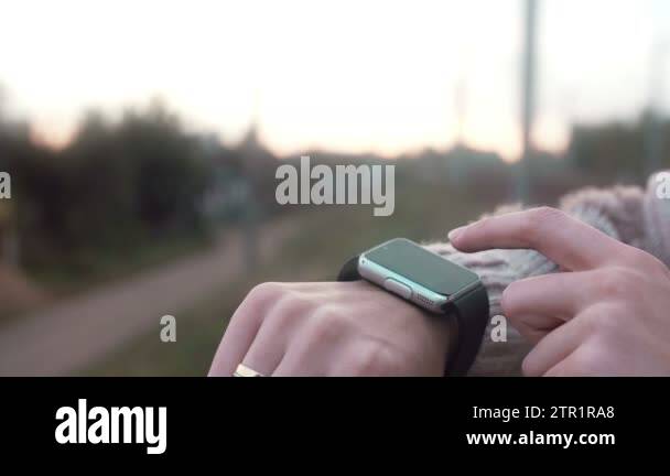 Woman using her smartwatch touchscreen device on a countryside ...