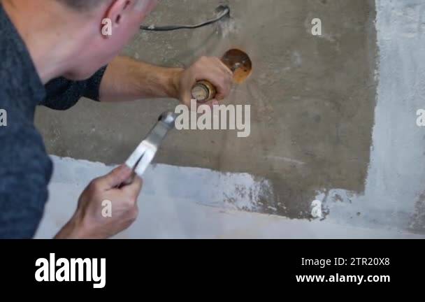 Installation of socket boxes in a brick wall. A male worker dismantles ...