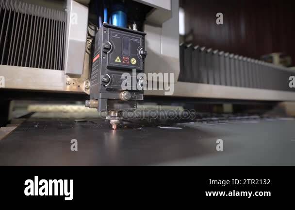 Industrial laser cutter with sparks. The programmed robot head cuts ...
