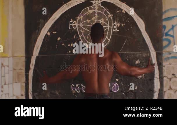 strong angry black man standing in ruins, taking up and squeezing his ...