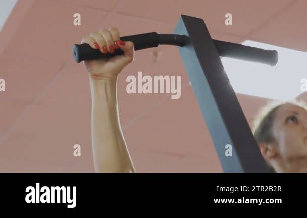 Fitness coach of the sports club does pull-ups on the simulator for ...