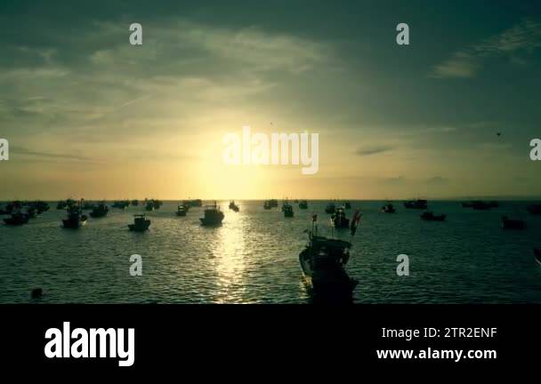 Drone footage of several dozen Asian fishing boats at sunset, an aerial ...