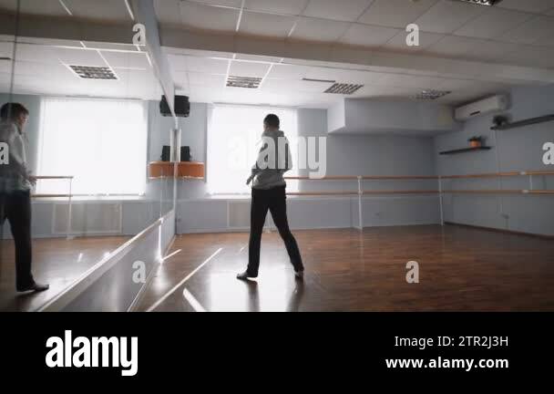 Young beautiful dancer jumping and spinning near the mirror in ballroom ...