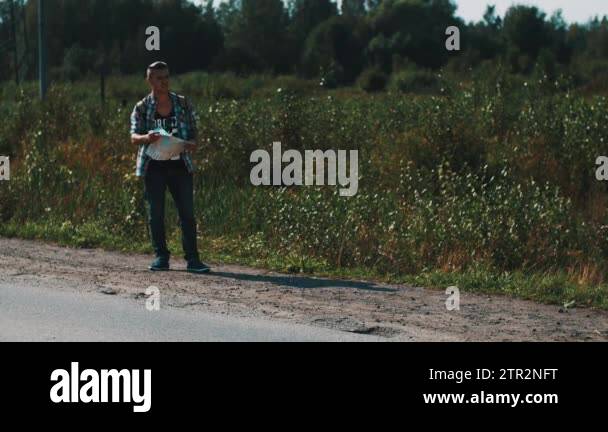 Young boy hitchhiking at roadside. Traveler. Thumb up. Map in hands ...