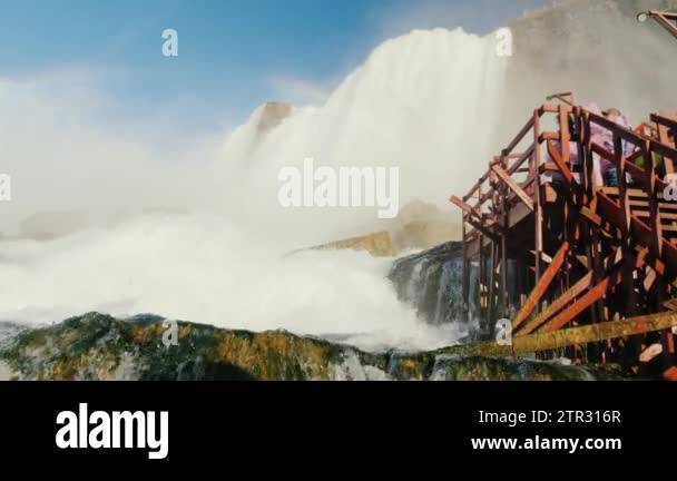 Mighty Niagara Falls and a wooden platform on the side for tourists. A ...