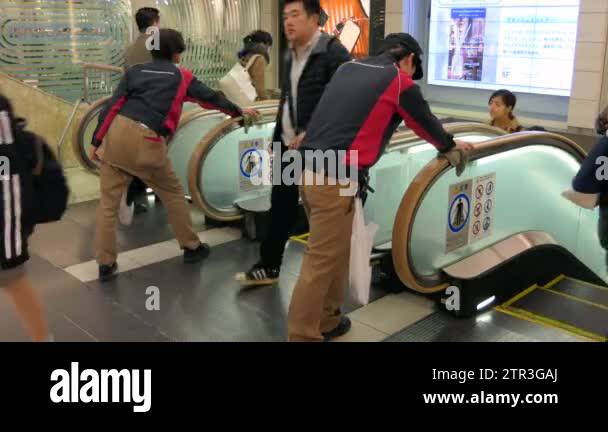 TOKYO, JAPAN - MARCH 2018 - Staff workers cleaning the escalator ...