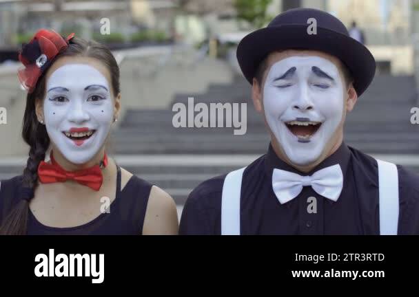 Two funny mimes play a scene. Girl and guy gesticulates their facial ...