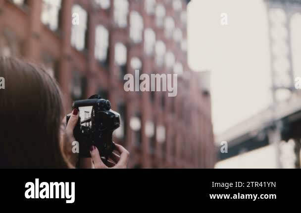 Back view professional female photographer with camera takes pictures ...