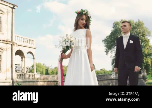 The groom coming to bride, touching her and kissing near castle. 4K ...