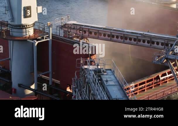 Close panorama of ship loading grain crops on bulk freighter via trunk ...