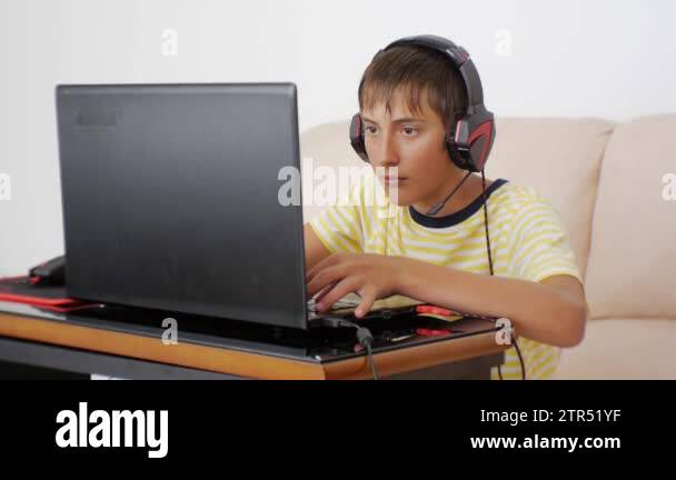 Teenager using laptop. Video game addicted teen with headphones glued ...