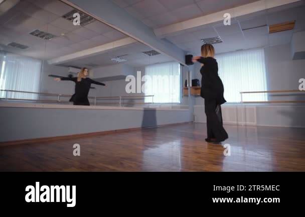 Beautiful white-haired woman in silk black suit dancing in classroom ...