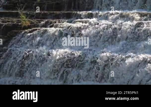Close up slow motion view panning down the rocky stepped cliff of the ...