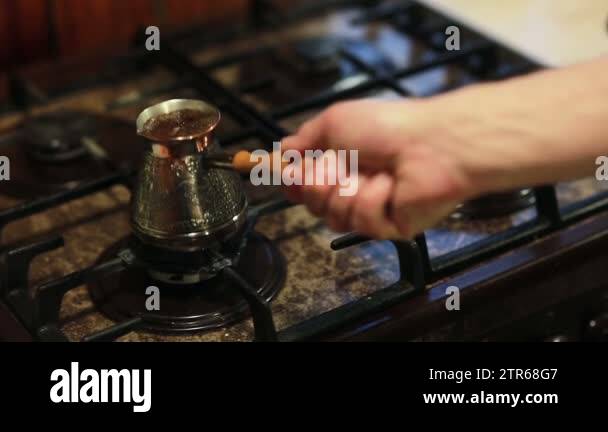 Coffee boiling in a coffee pot. Hands of a man taking the pot and ...