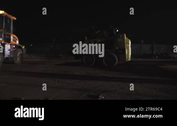 Skid-steer loader is driving by loader on the construction site Stock ...