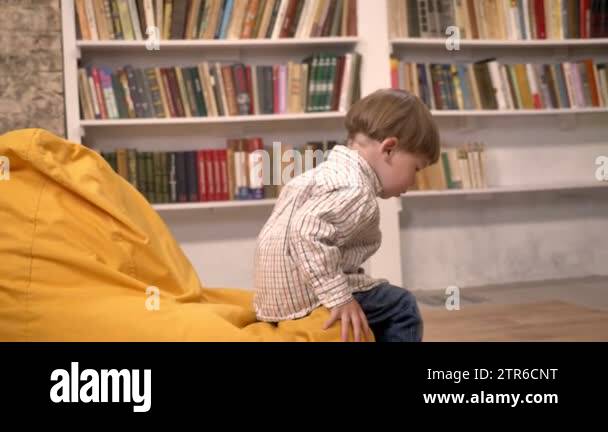 Little cute kid sitting on chair and catching ball from somebody ...