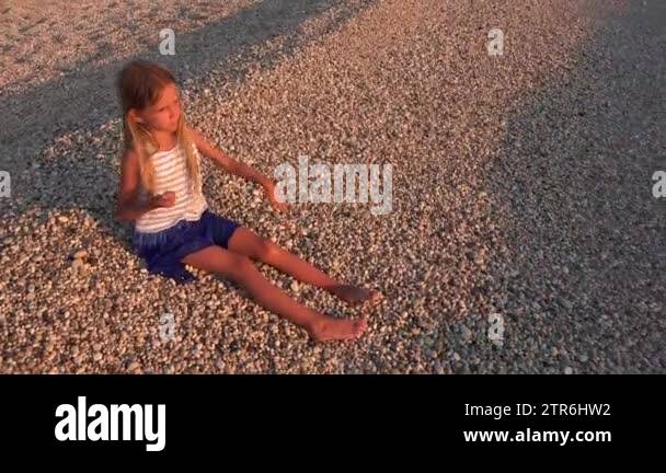 Girl Playing on Beach in Sunset, Smiling Child Throwing Pebbles in Sea ...