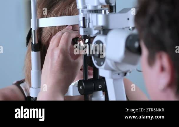 Female Doctor checking eyes with modern medical device. Eye examining ...