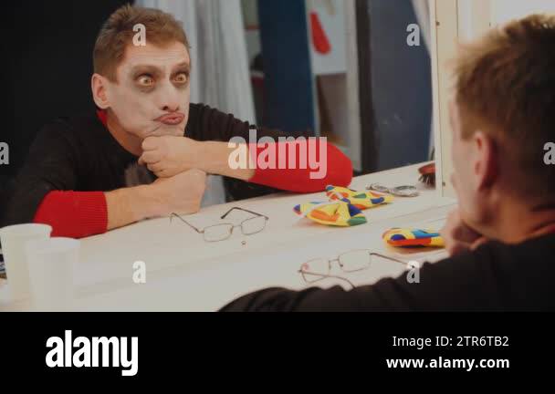 clown mime looking at herself in the mirror and makes faces, after the ...