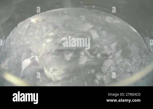Chemist mixing powder and liqiuid with a glass stick inside the glass ...