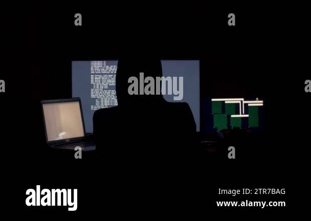 Hacker in hood cracking code using computers in dark room Stock Video ...