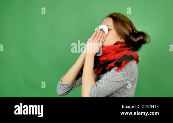 The young, attractive brunette is ill. The girl cleans her nose, she ...