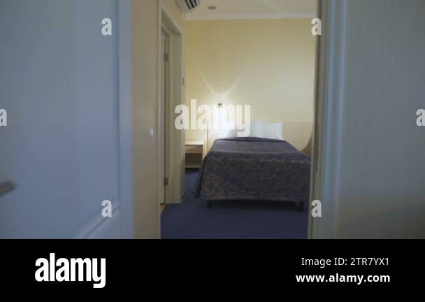 Cozy hotel room with two neatly made beds and lamps on the wall. Camera ...