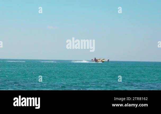 A firefighting aircraft in an emergency situation, skimming water from ...