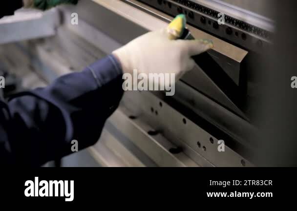 Worker hands bend metal sheet on a modern bending industrial machine at ...