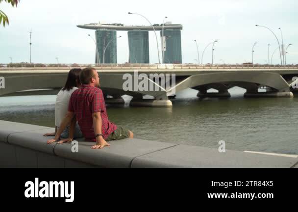 Man and woman are sitting on a parapet on the river embankment ...