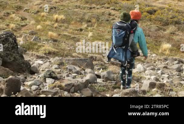 Trekking in Batea Mahuida volcano. Lady carrying baby walking down the ...