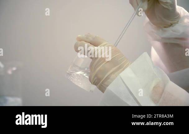 Chemist mixing viscous liquid in a flask with a glass tube. Laboratory ...