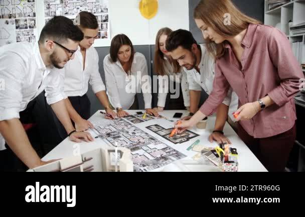 Four architects standing and planning around a table while looking down ...