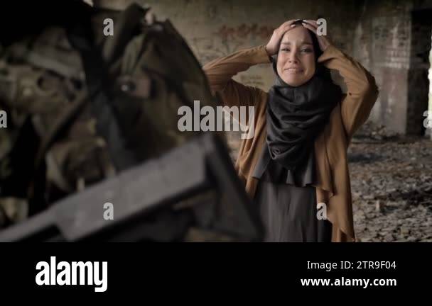 Young muslim woman in hijab screaming and crying behind soldier with ...