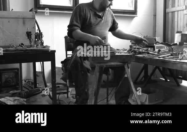 Craftsman is making figure with metal wire in his workshop. Artist is ...