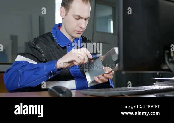 Male engineer measures the item and enter the data into a computer ...