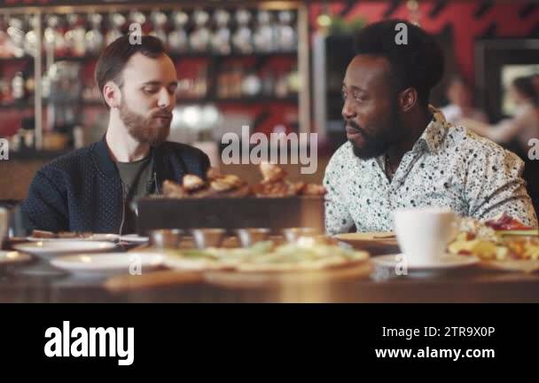 two young men eat a steak in a restaurant. two friends sit at a table ...